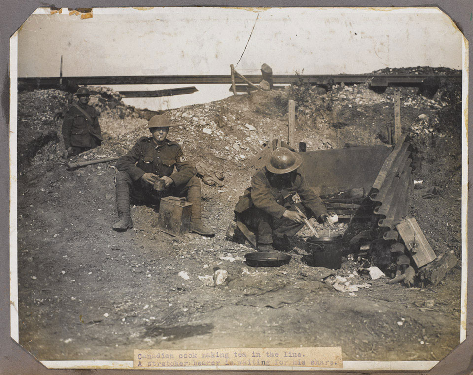 'A Canadian cook making tea in the line. A stretcher bearer is waiting ...